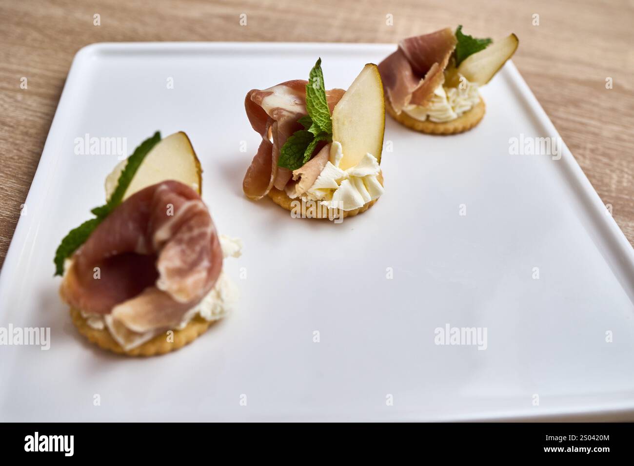 Bite-sized crackers topped with cream cheese, prosciutto, pear slices ...
