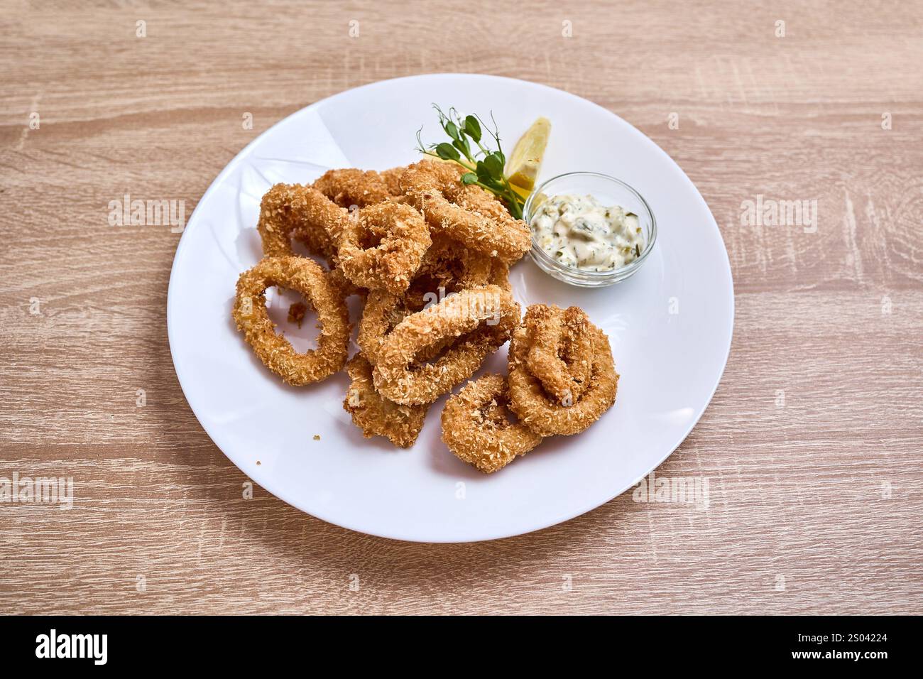 Golden-fried calamari rings served with tartar sauce and a lemon wedge ...