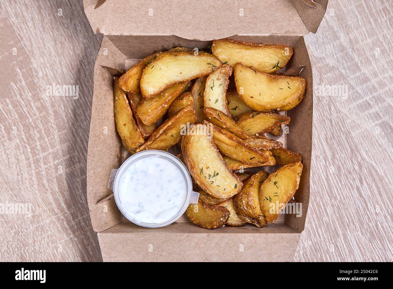 Crispy baked potato wedges with sauce in a cardboard box Stock Photo ...