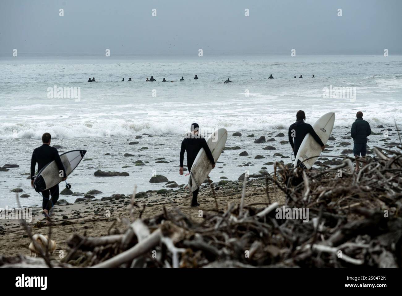 Surfers walk along Rincon Point in Ventura County, Calif., on Monday ...