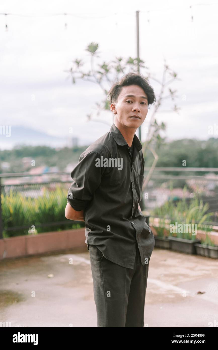 Southeast Asian man standing with hands hidden behind his back. Calm ...
