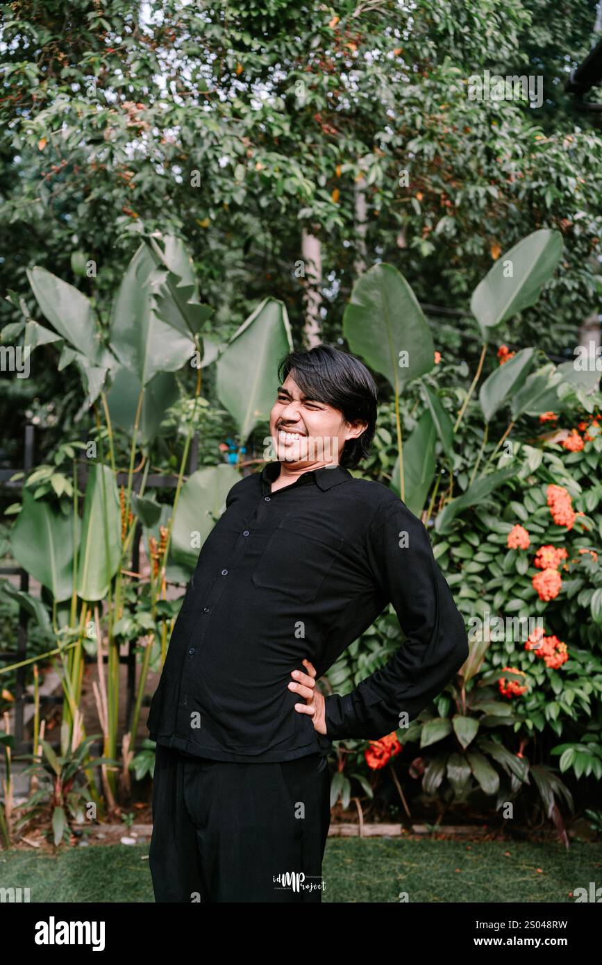 A Southeast Asian man posing with hands on his waist, showcasing a ...