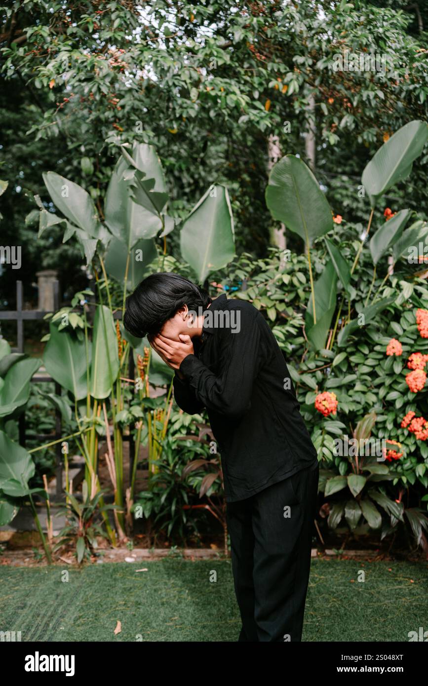 A Southeast Asian man caught mid-sneeze, showing a natural and candid ...