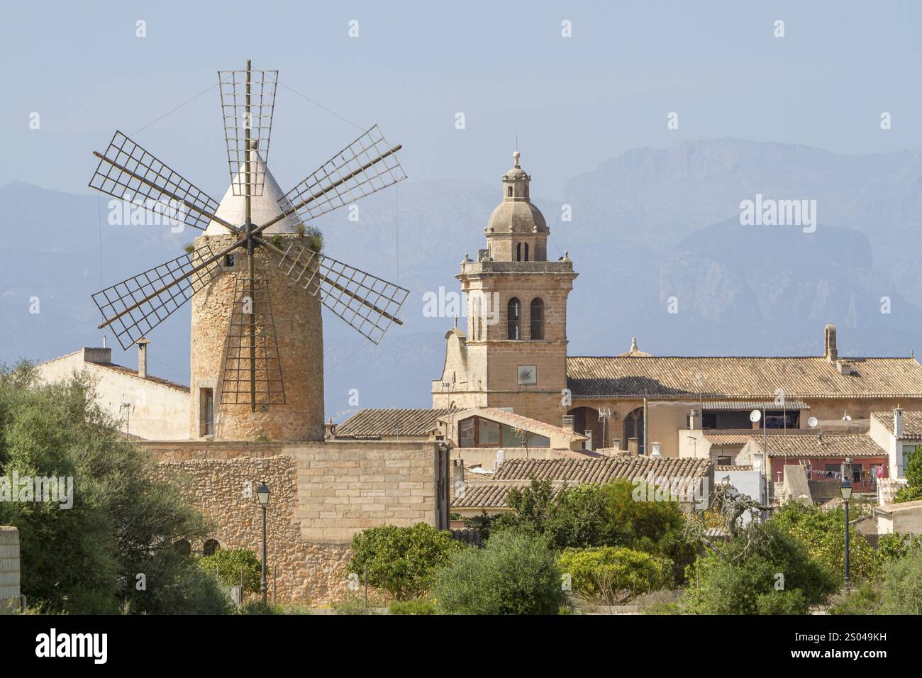 Mediterranean village with windmill and church against a mountain ...