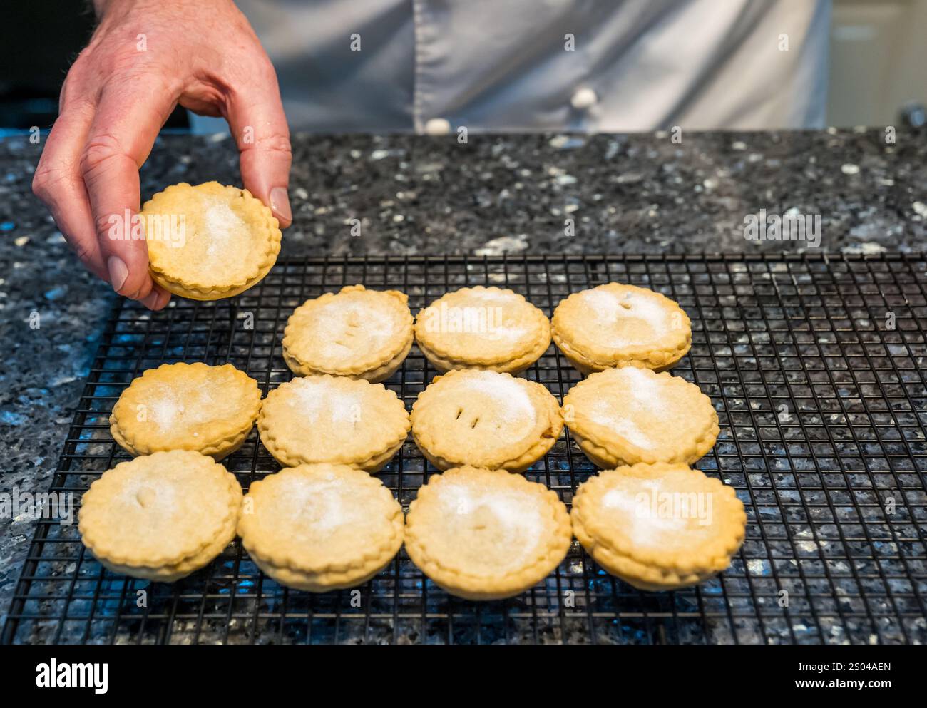 Senior man in chef whites with freshly baked mince pies on a cooling ...