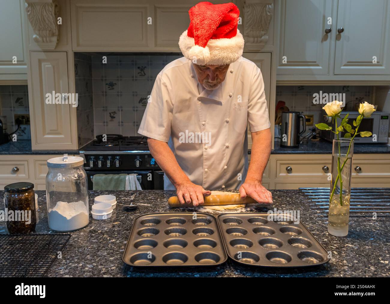 Senior man wearing chef whites and Santa hat making mince pies for ...
