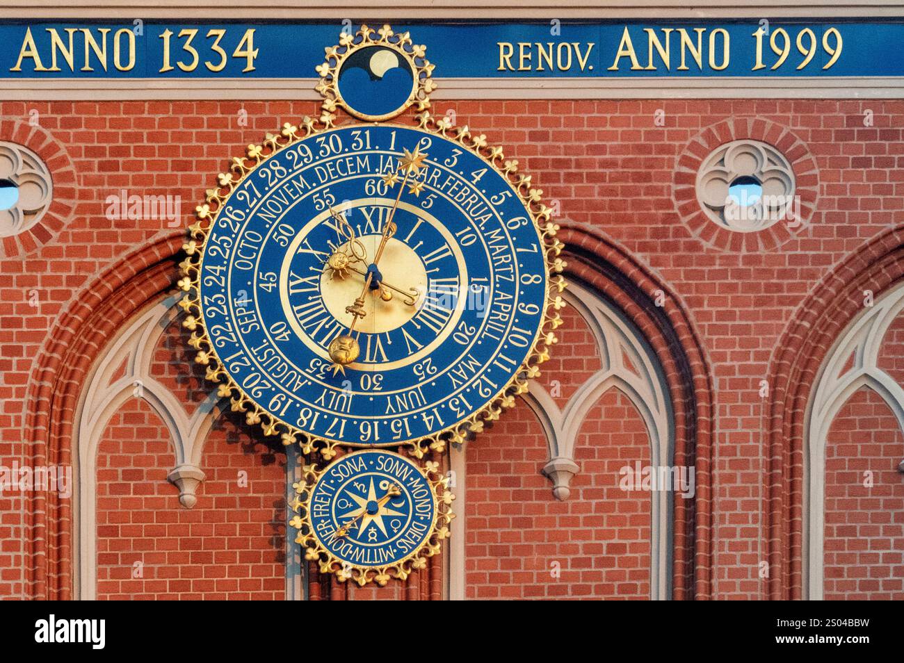 A detailed astronomical clock on a brick wall, featuring a blue and ...