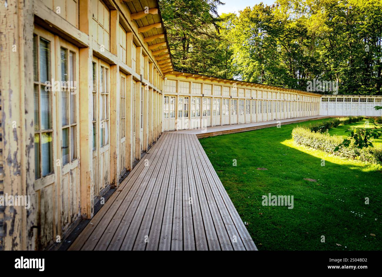 A wooden walkway curves alongside a vintage building with large windows ...