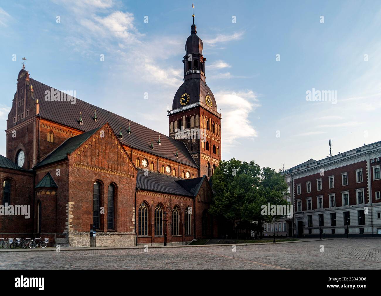 A historic brick church with a tall clock tower, surrounded by a ...