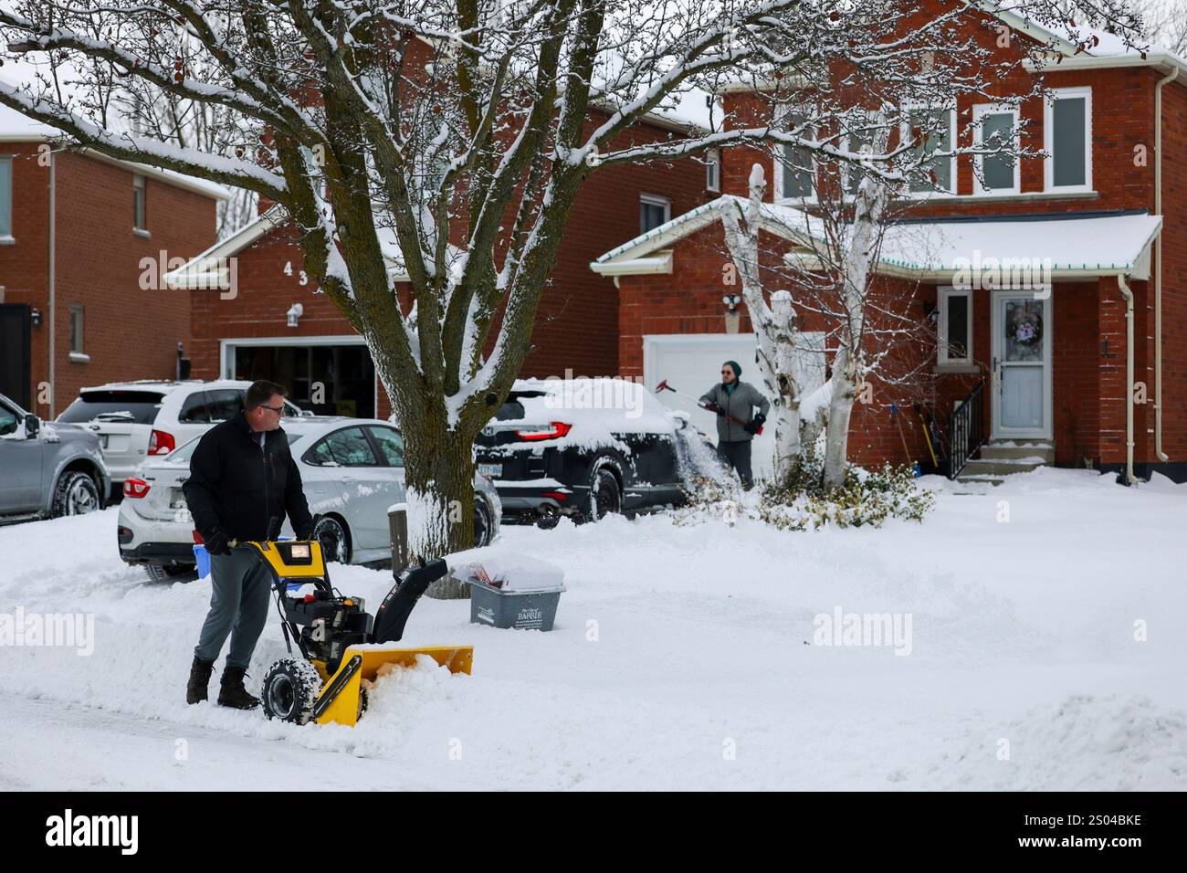Barrie, Ont., resident Sean Wood, left, helps his neighbours plow their ...
