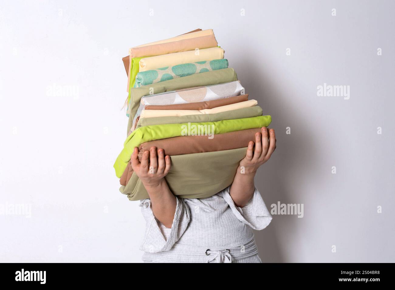 Woman holding stack of clean bed linens on white background Stock Photo ...