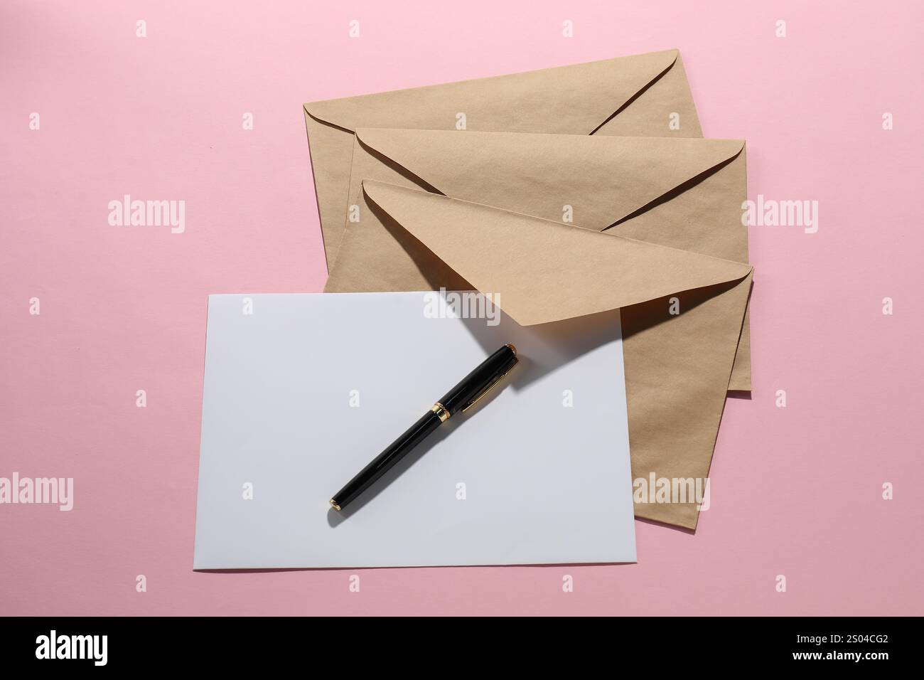 Kraft paper envelopes with letter and pen on pink background, flat lay ...
