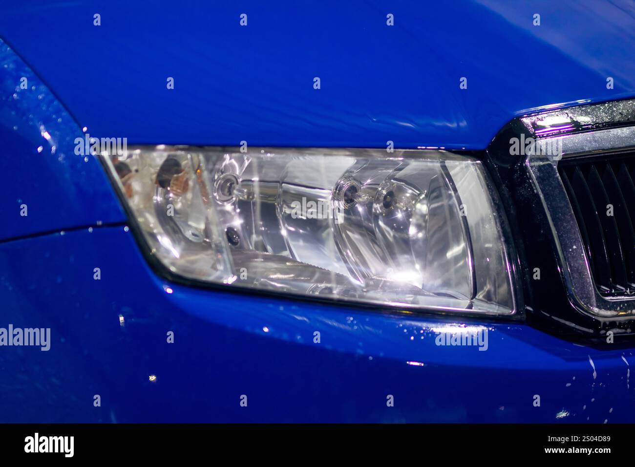 This image shows a detailed close up of the headlight of a blue car ...