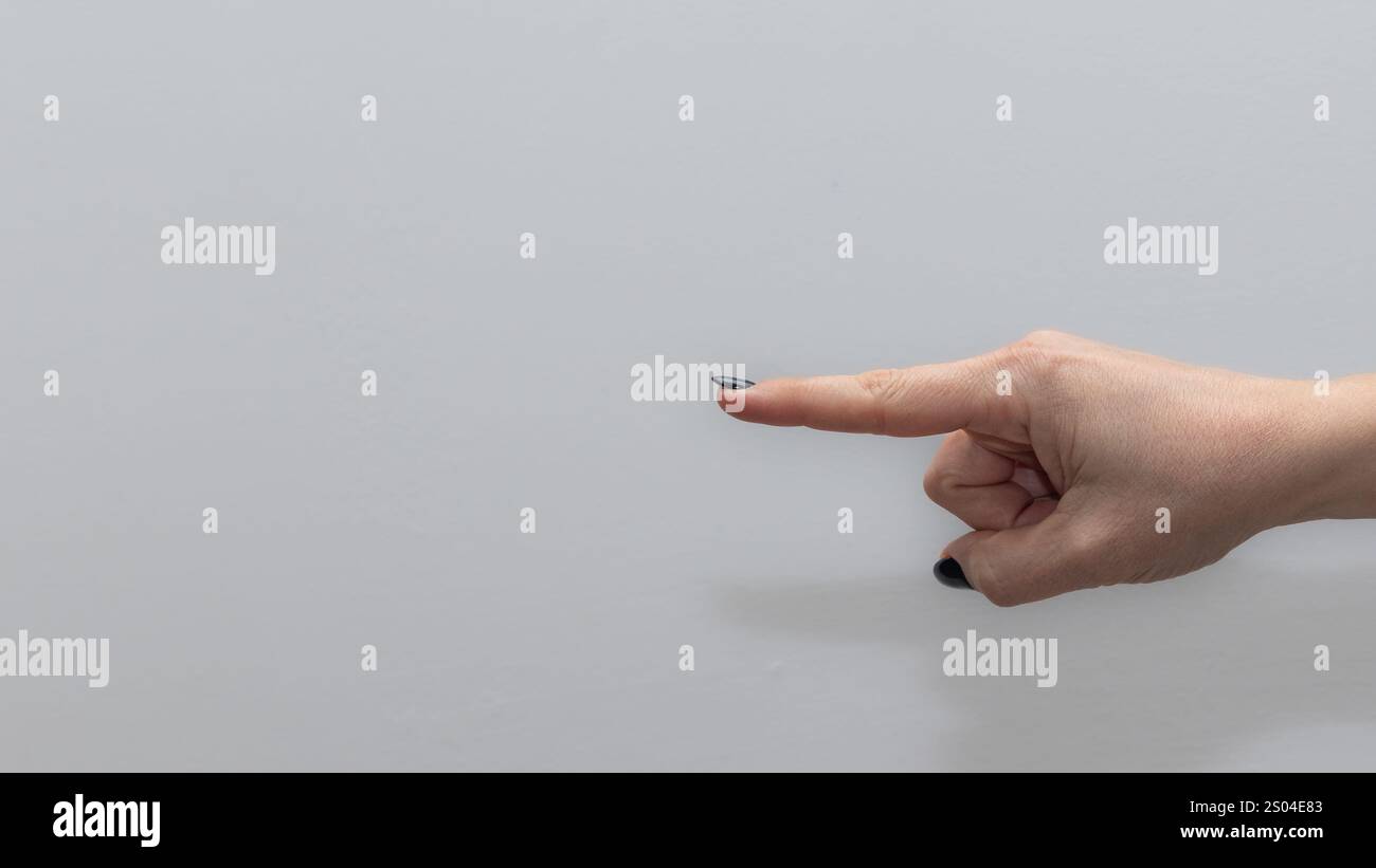 Female hand with a single finger pointing right, against a clean gray ...