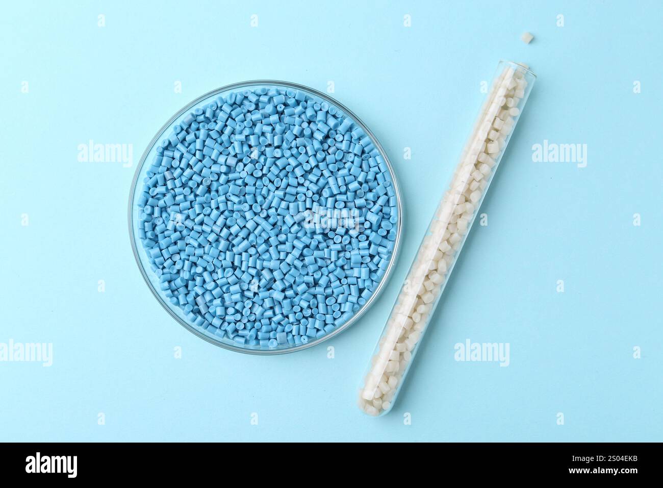 Colorful plastic granules in petri dish and test tube on light blue ...