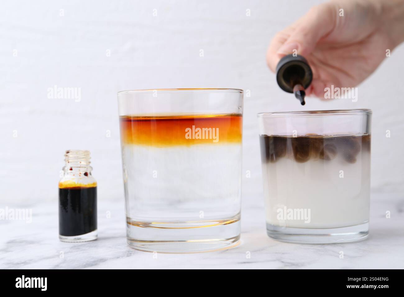 Iodine starch test. Woman dripping aqueous iodine into glass of water ...