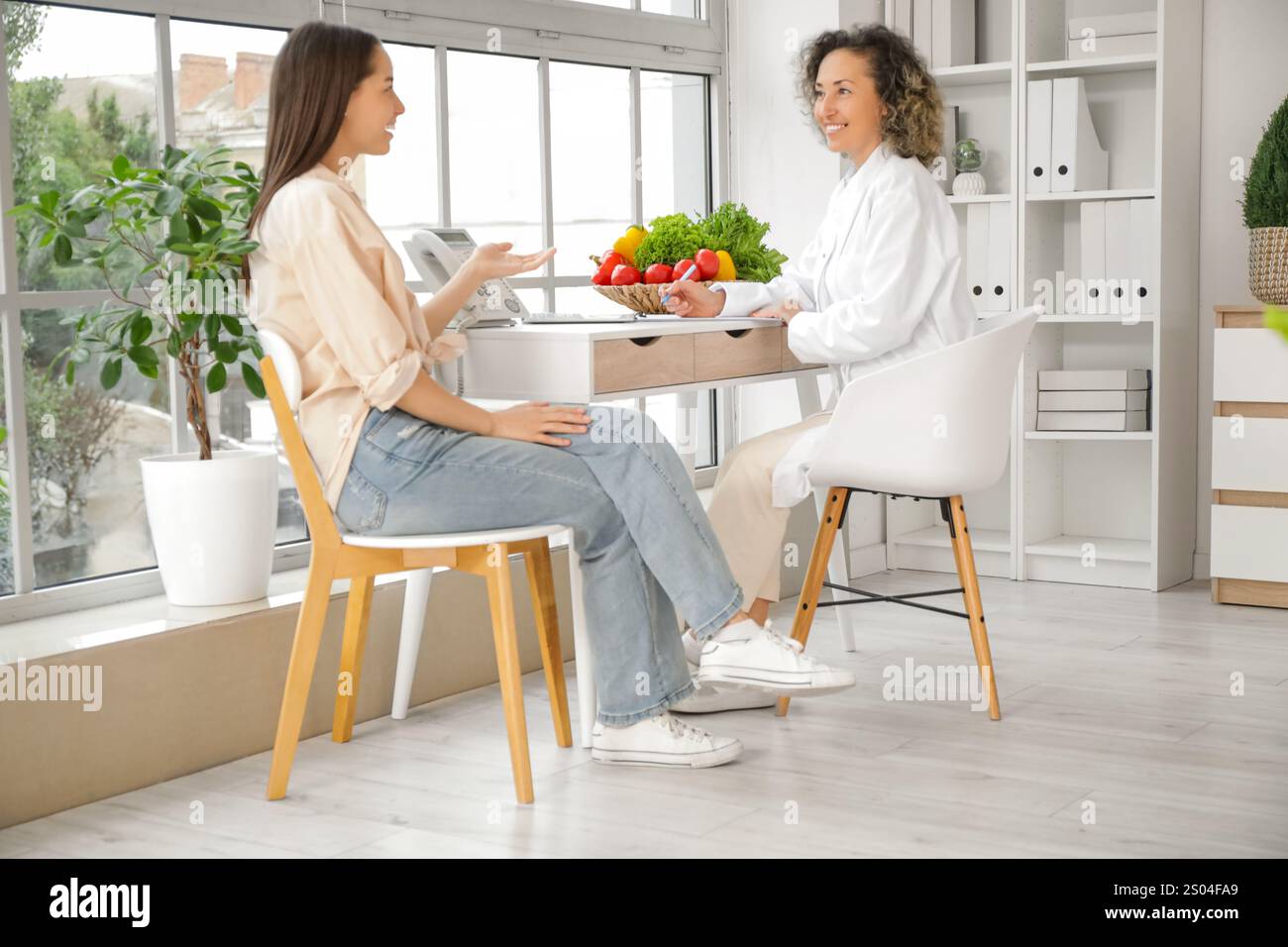 Mature female nutritionist making meal plan for client at table in ...