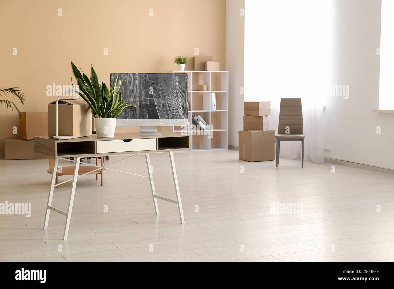 Workplace with wrapped computer monitor and boxes in office on moving ...