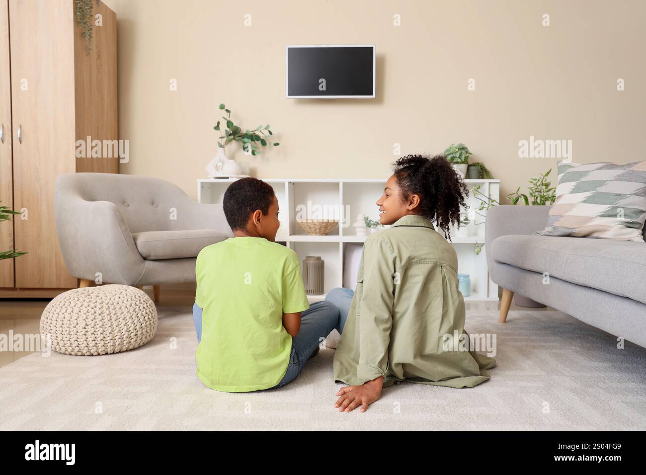 Cute happy African-American children watching cartoons on TV at home ...