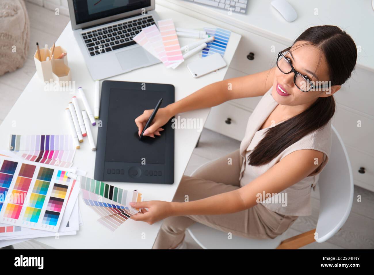 Female Asian graphic designer with tablet and color palettes working at ...