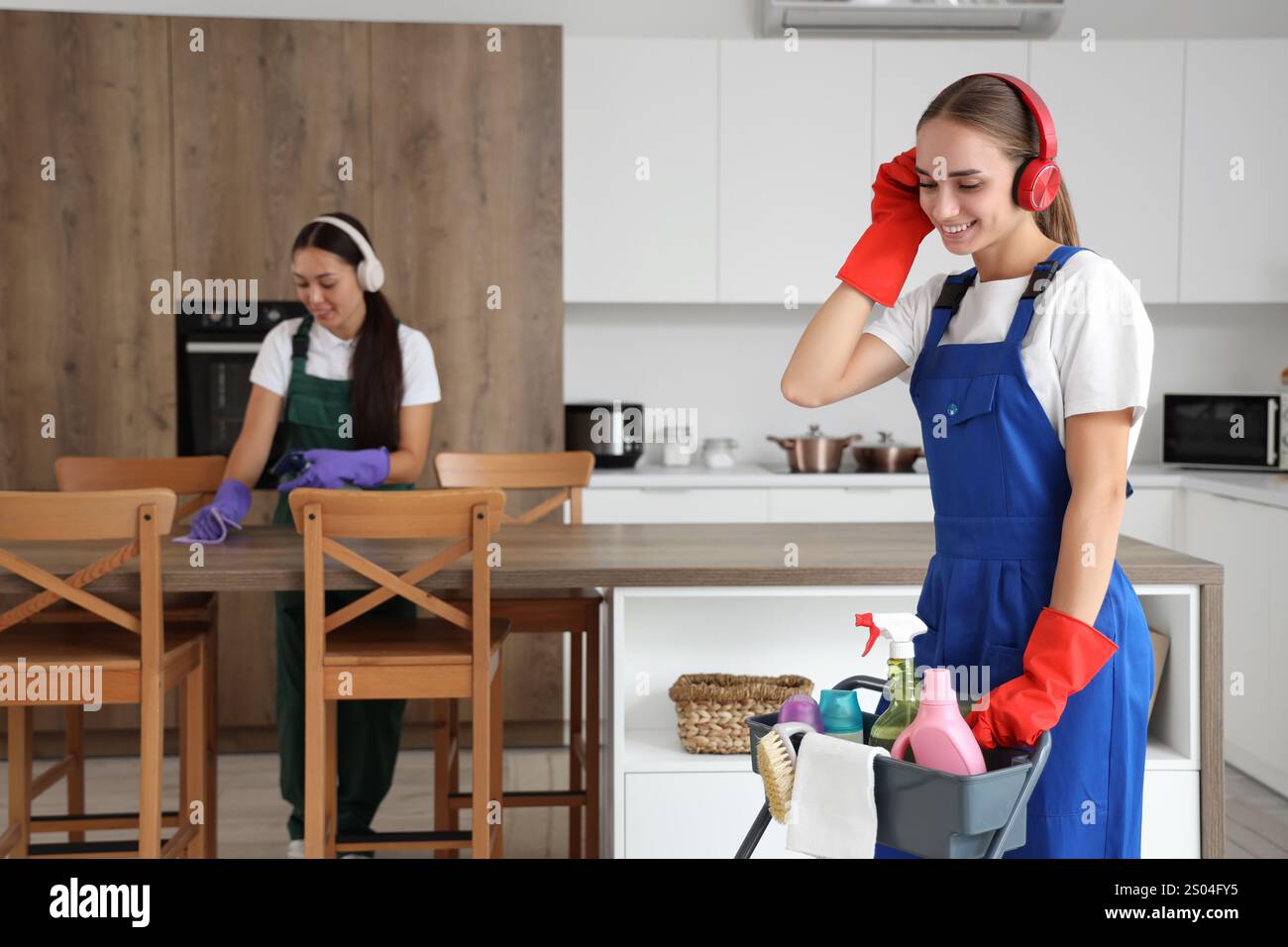 Female janitor with headphones and trolley in kitchen Stock Photo - Alamy