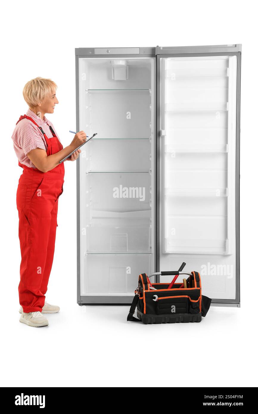 Female worker with clipboard near refrigerator on white background ...