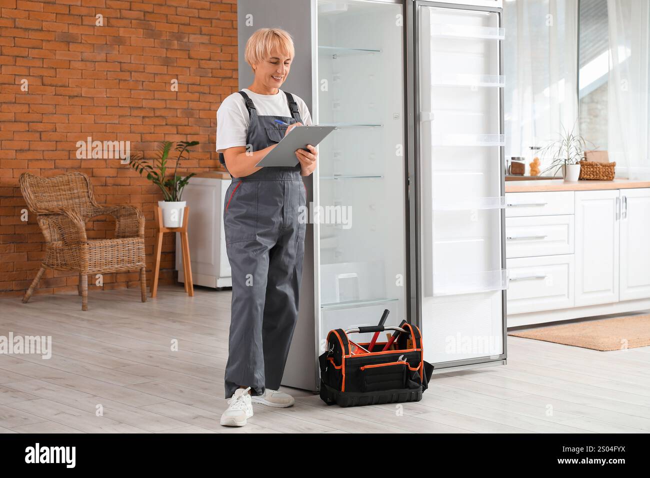 Female worker with clipboard near refrigerator in kitchen Stock Photo ...