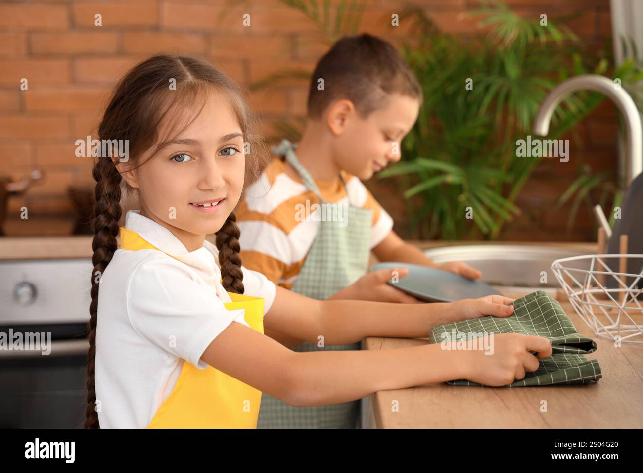 Little girl and her brother cleaning dishes together in kitchen Stock ...