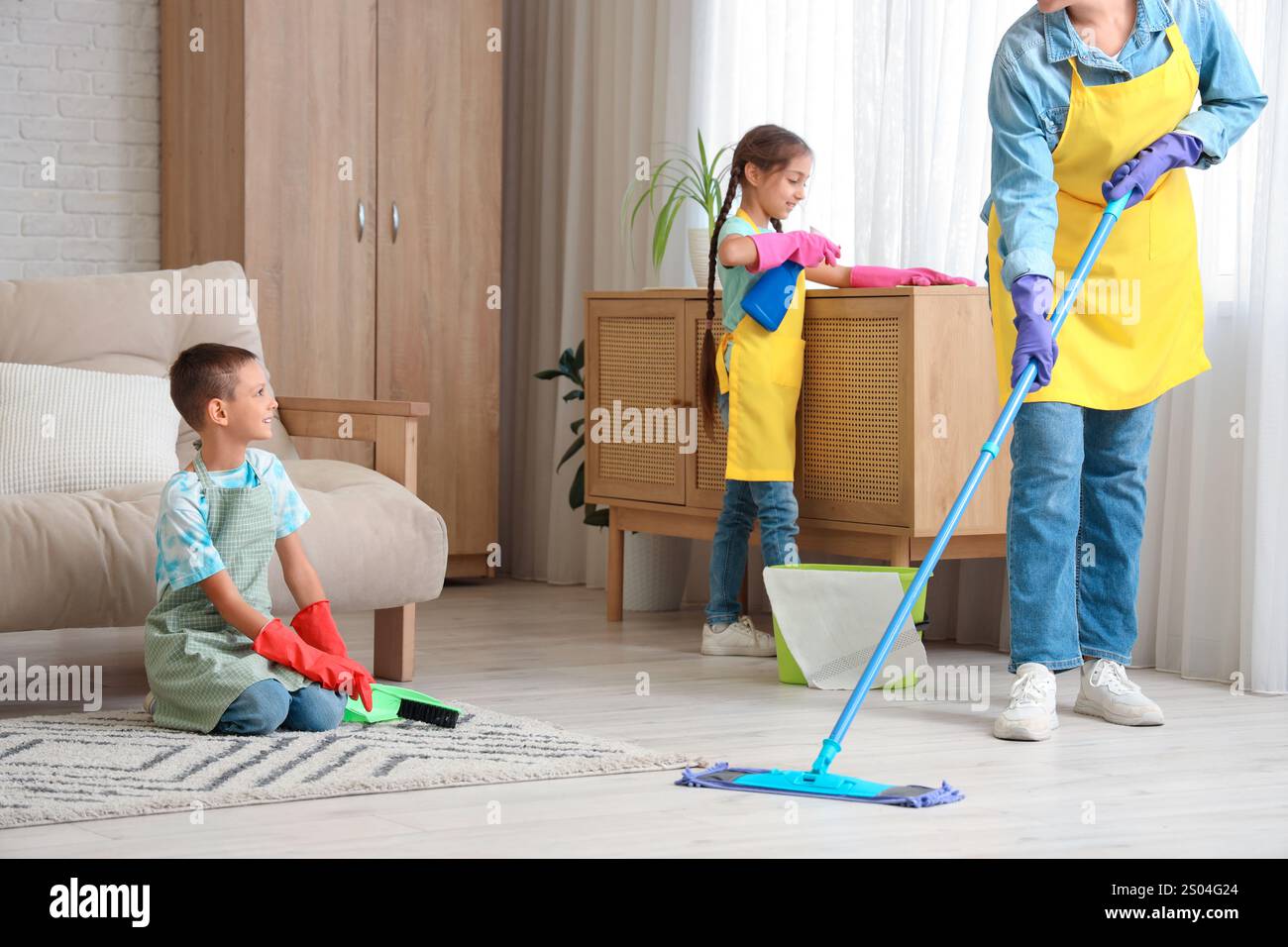 Cute little children helping their mother with cleaning routine at home ...