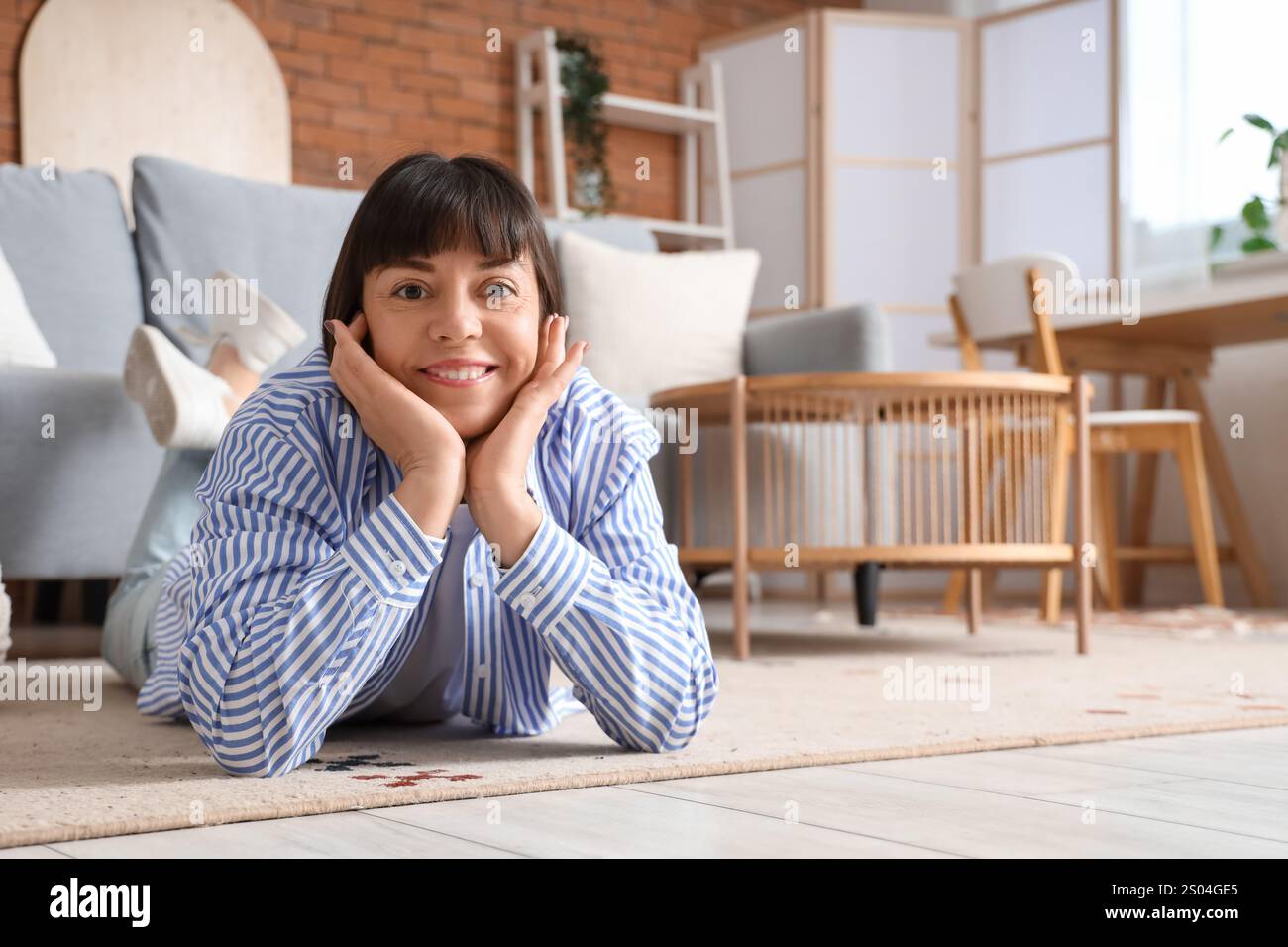 Beautiful woman lying on carpet at home Stock Photo - Alamy