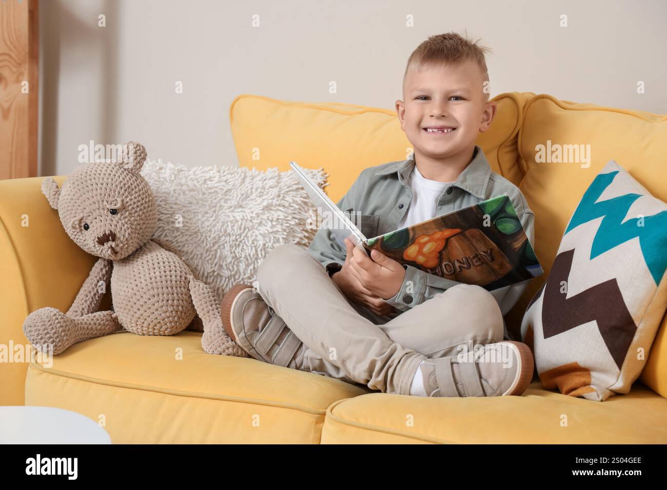 Cute little boy reading story on sofa at home Stock Photo - Alamy