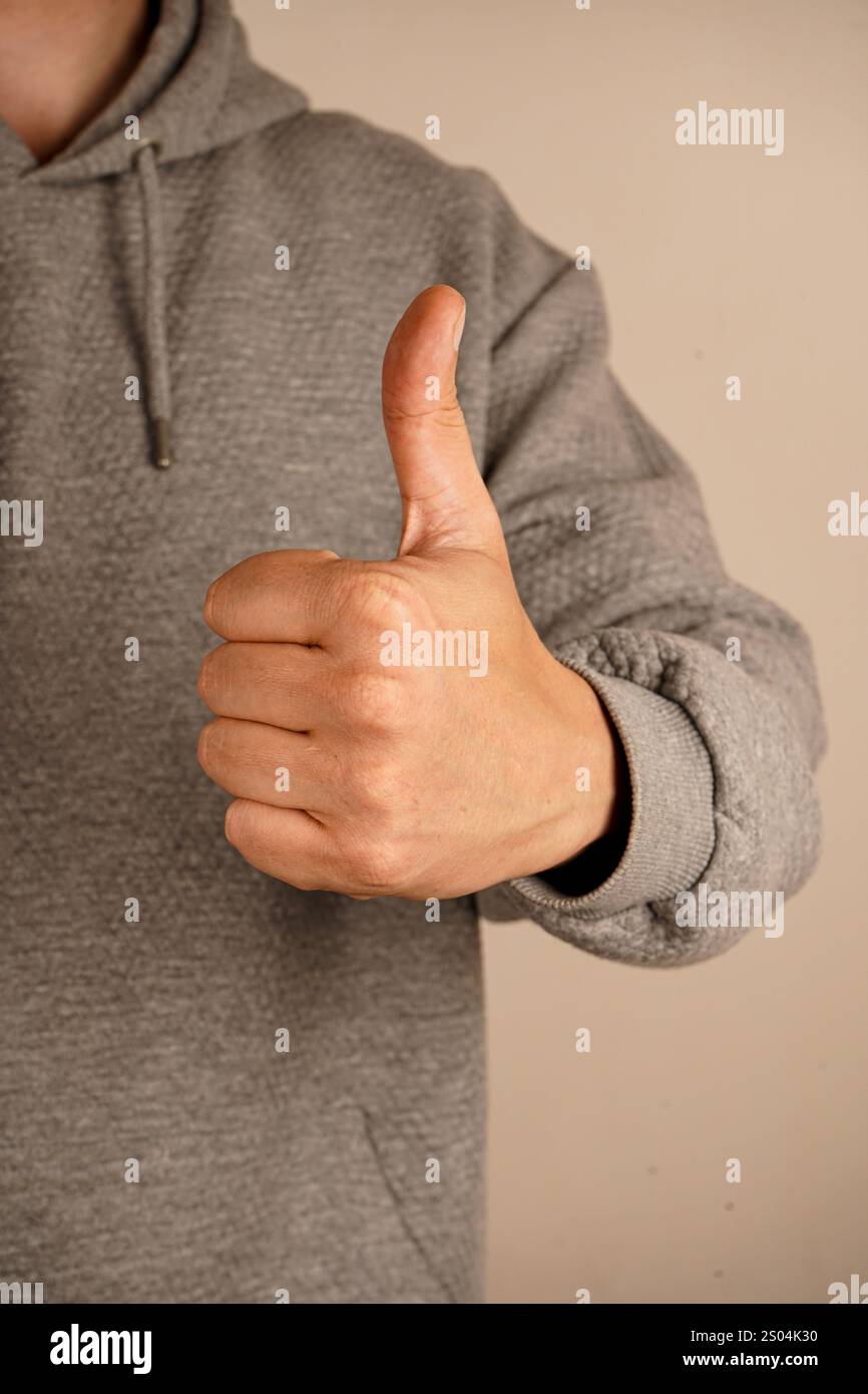 The hand shows a like. A thumbs up sign is displayed on a plain, bright ...