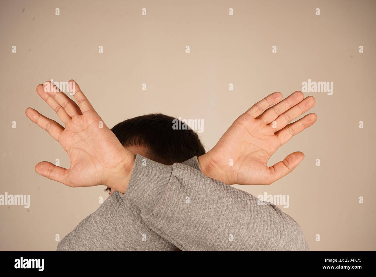 A man crosses his arms, holding his palms near his face as if in a ...
