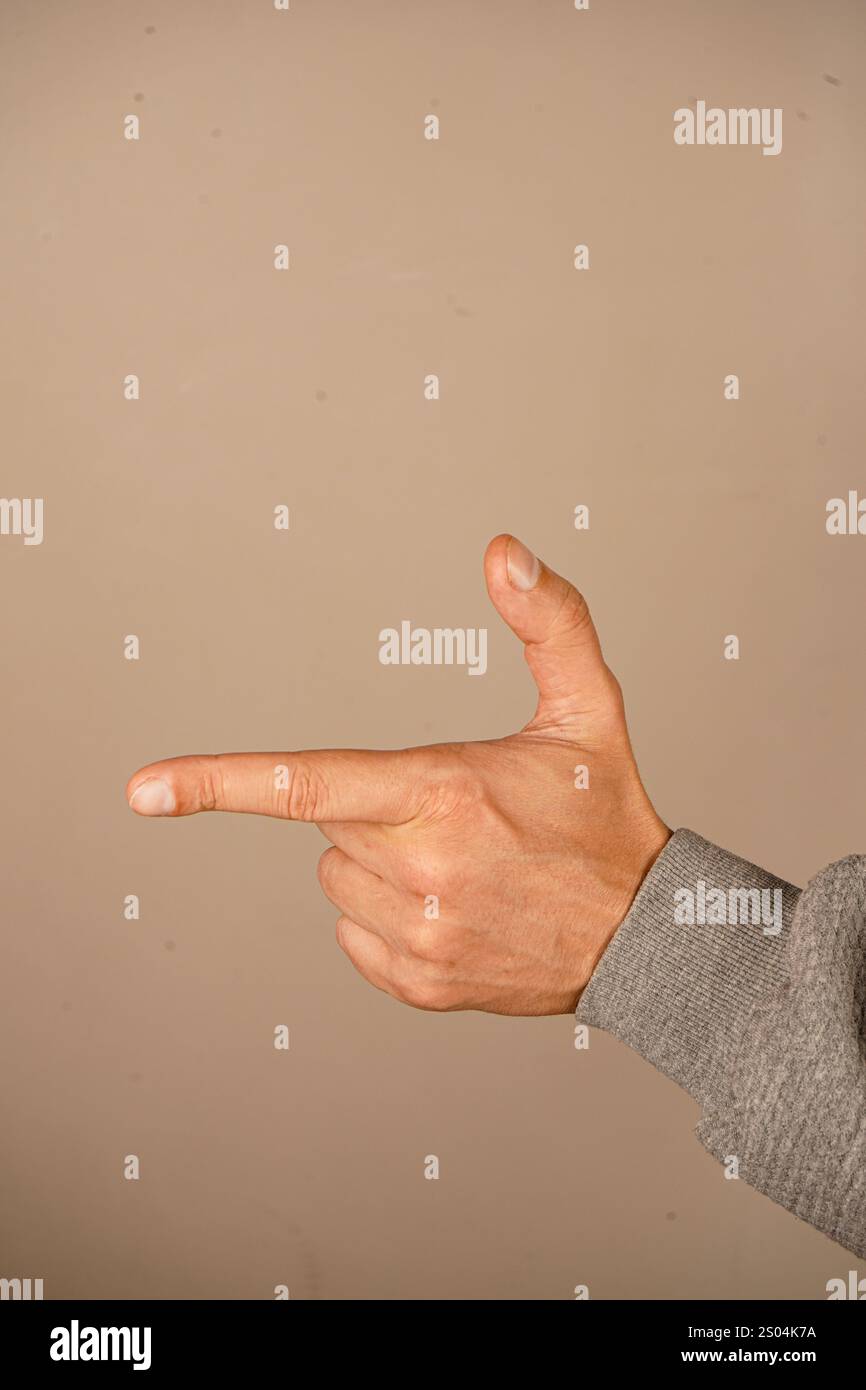 A hand gesture showing a pointing finger with the thumb raised, while ...