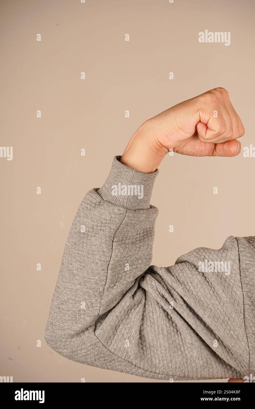 A flexed arm with a clenched fist highlights the muscular definition of ...