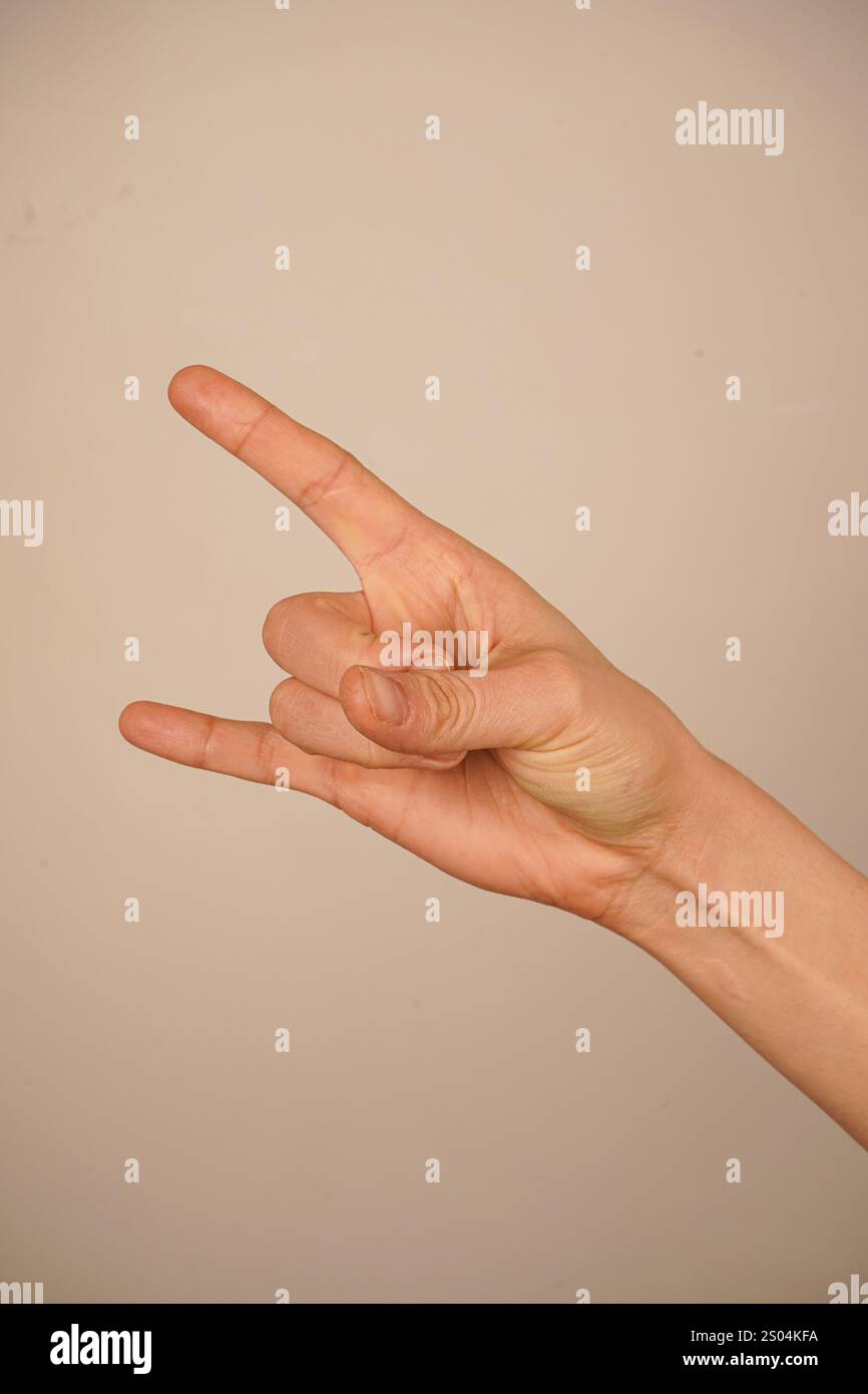 The "heavy metal" hand gesture is shown against a bright plain wall ...