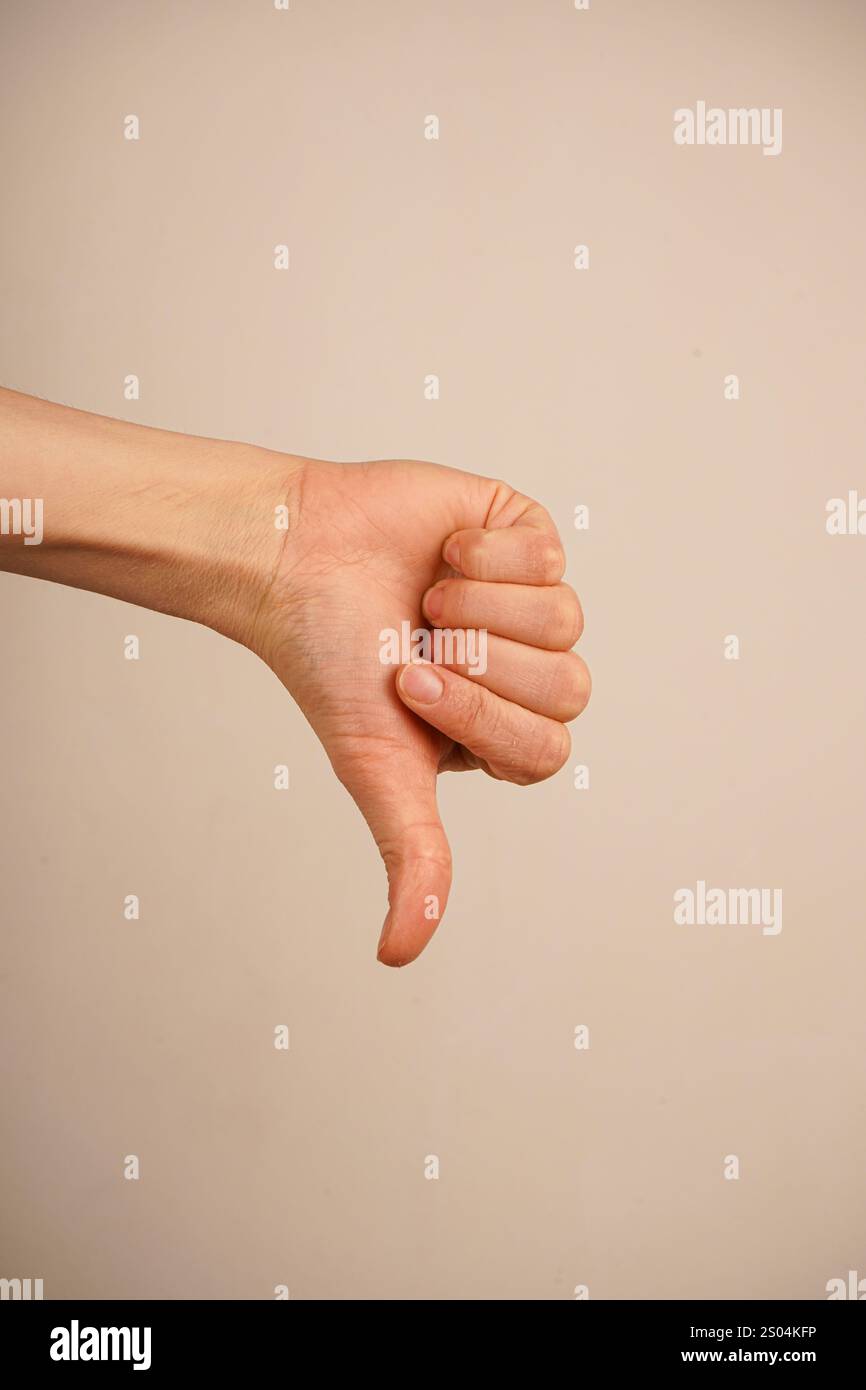 Thumbs down gesture shows dislike. Neutral background focuses the ...