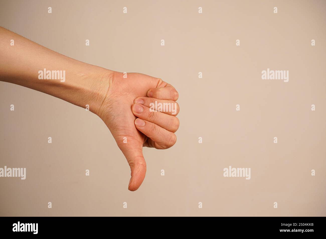 Thumbs down gesture shows dislike. Neutral background focuses the ...