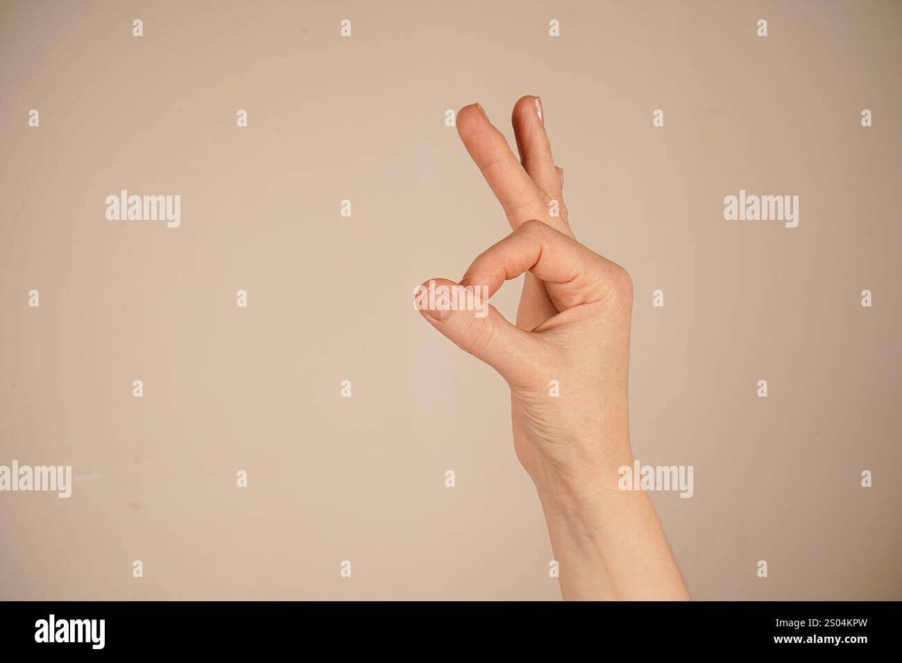 A close-up of a hand showing the okay sign against a light, neutral ...