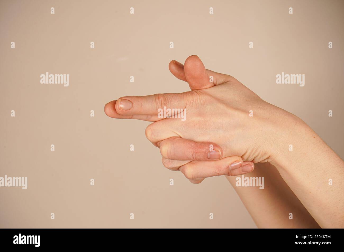 A close-up of two hands. They form a gun gesture: the index and middle ...