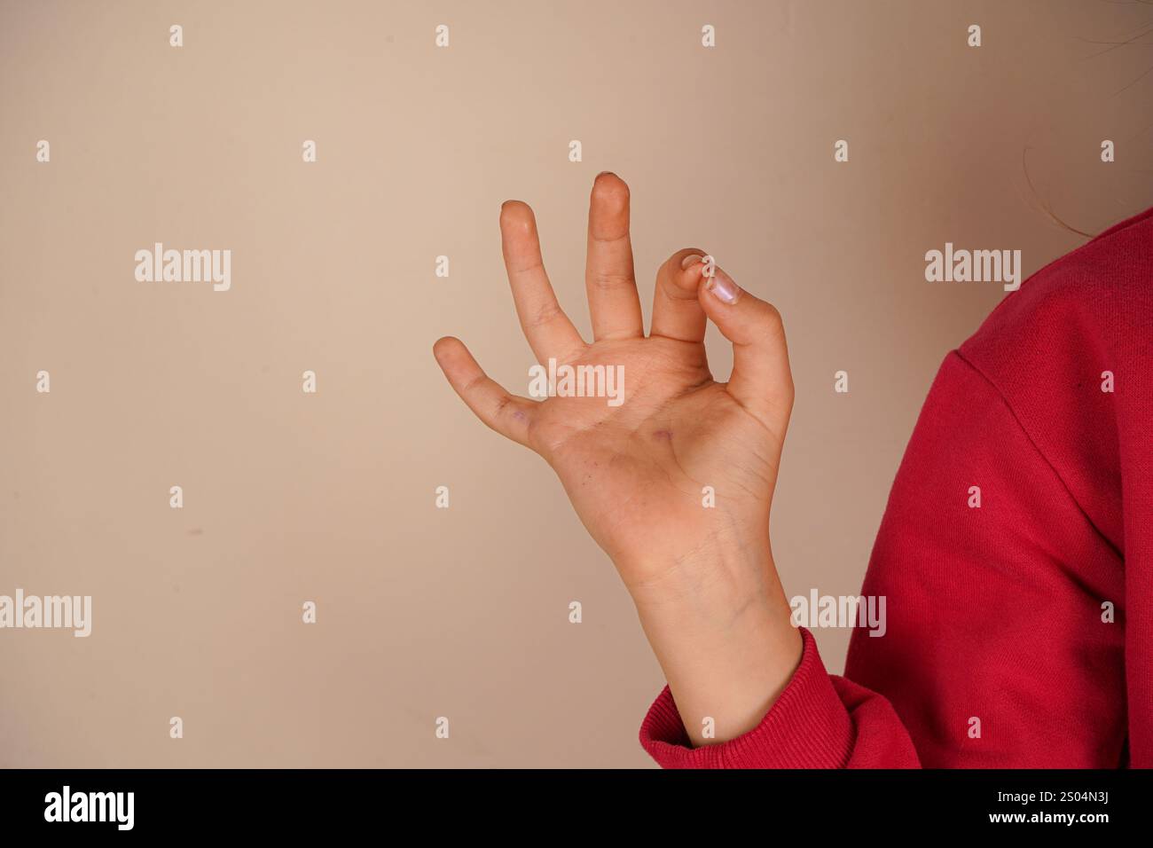 A close-up of a human hand forming an "okay" gesture against a light ...