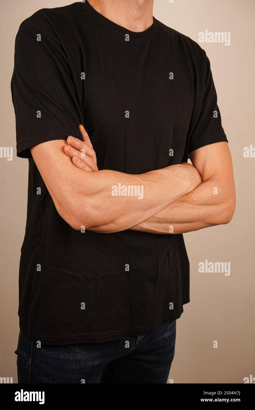 A man folds his arms in a protective pose, hands resting on each other ...