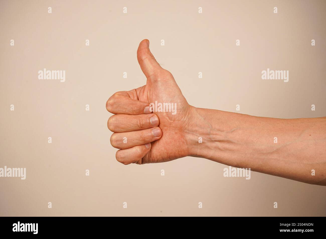 The hand shows a like. A thumbs up sign is displayed on a plain, bright ...
