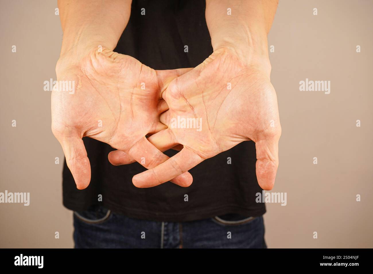 Hands locked behind the back against the background of a black T-shirt ...