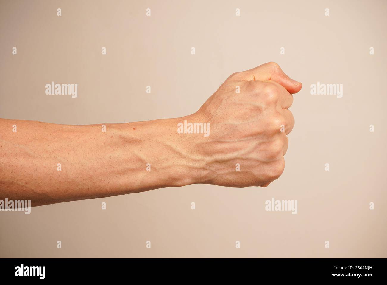 A man clenches his hand tightly into a fist, all the tendons and veins ...