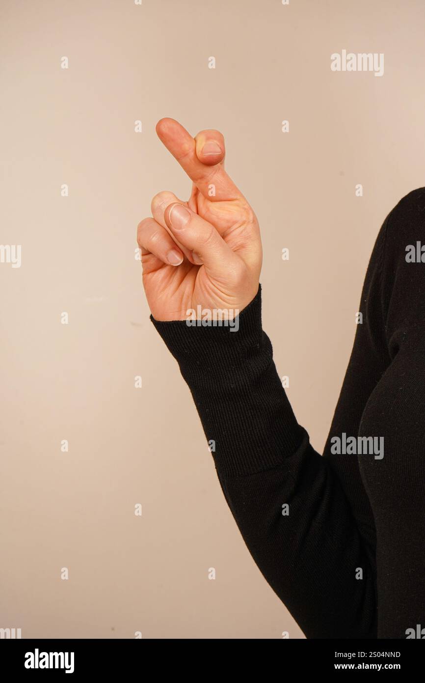 The index and middle fingers of the hand are crossed, a universal symbol of good luck. This ...