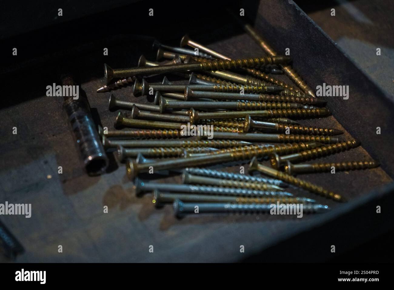 Metal screws are neatly arranged on a craftsman's workbench. The table ...