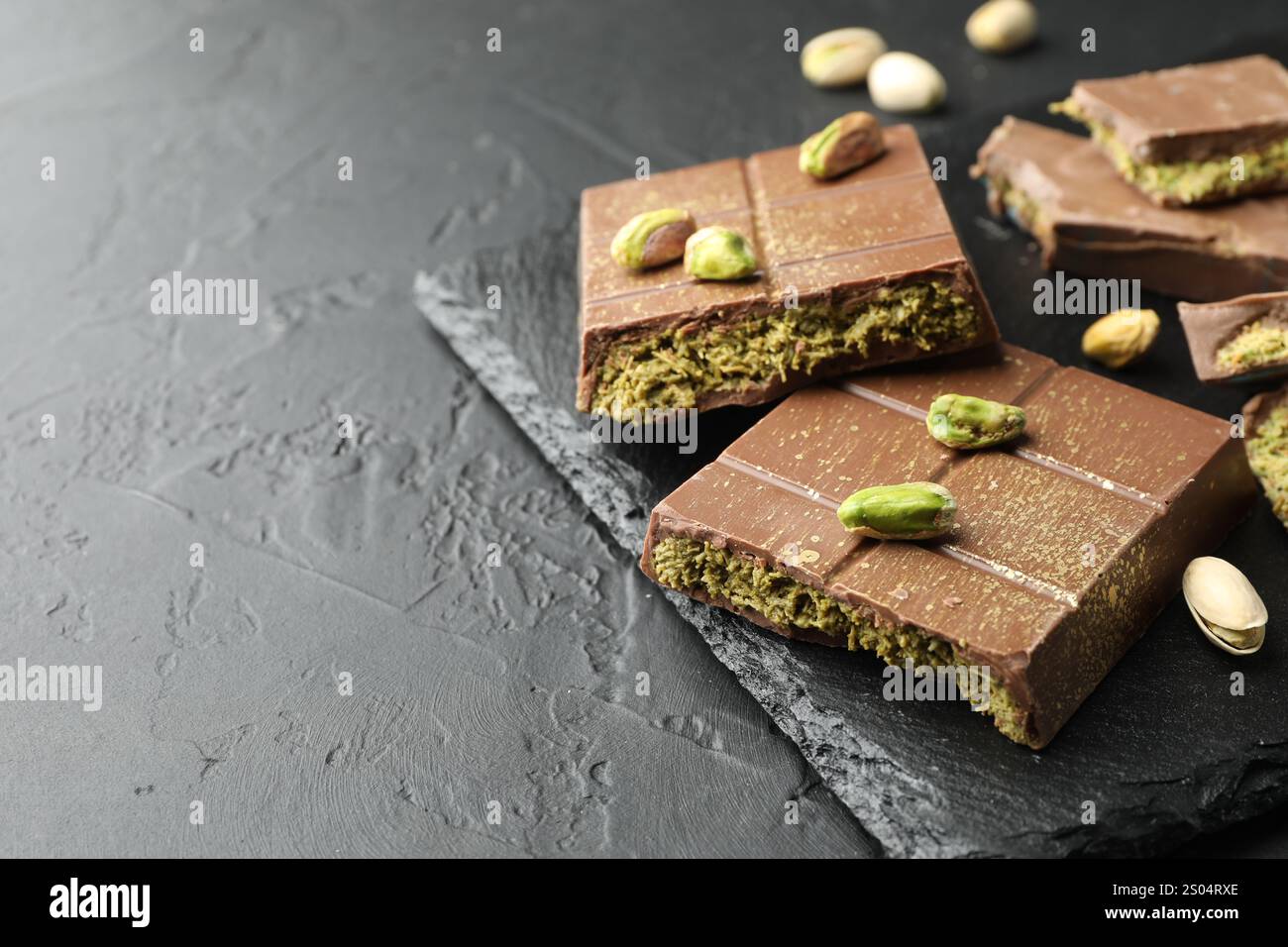 Pieces of Dubai chocolate bars with pistachios and knafeh on grey table ...