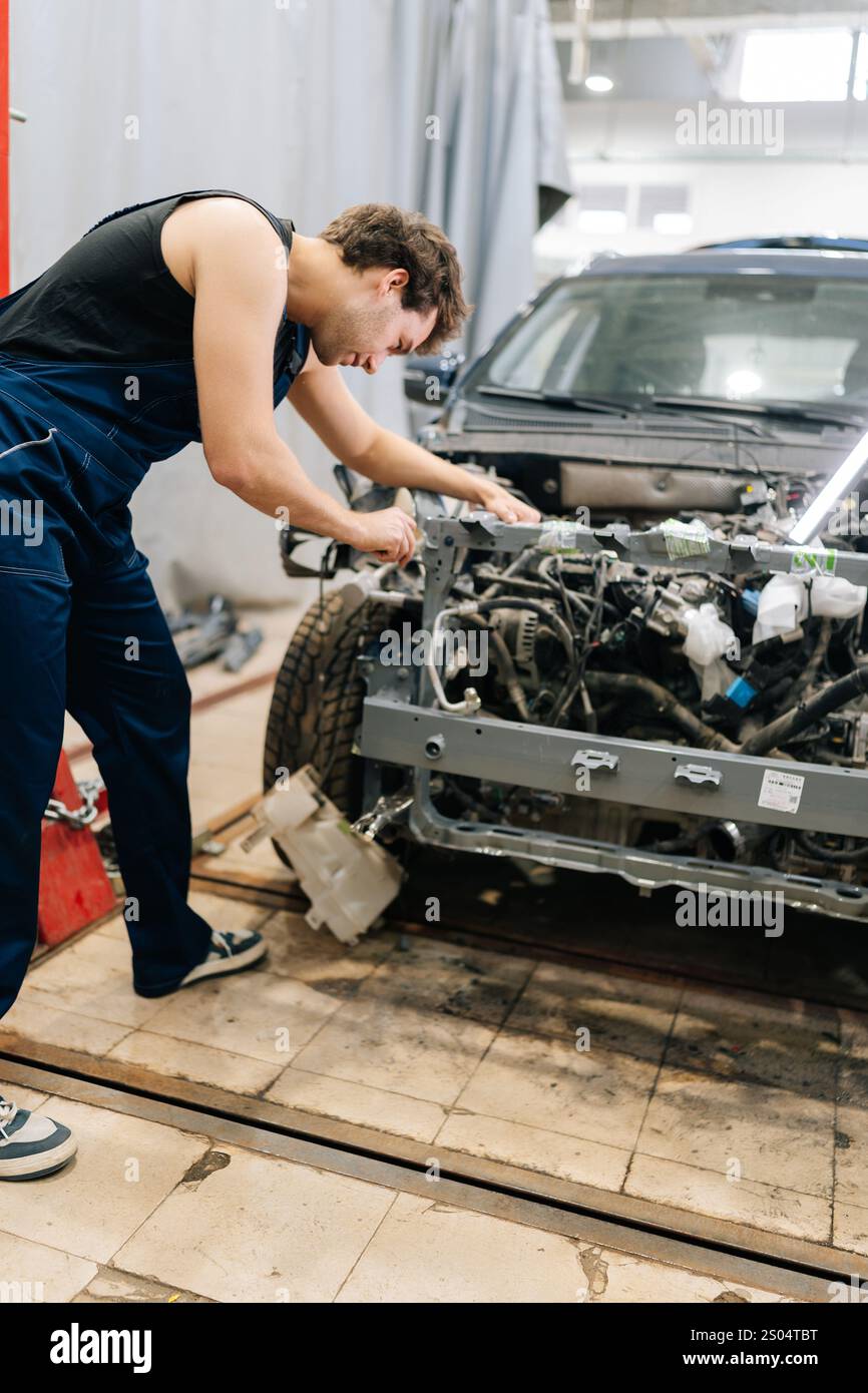 Vertica rear view of focused mechanic male in blue uniform inspecting ...