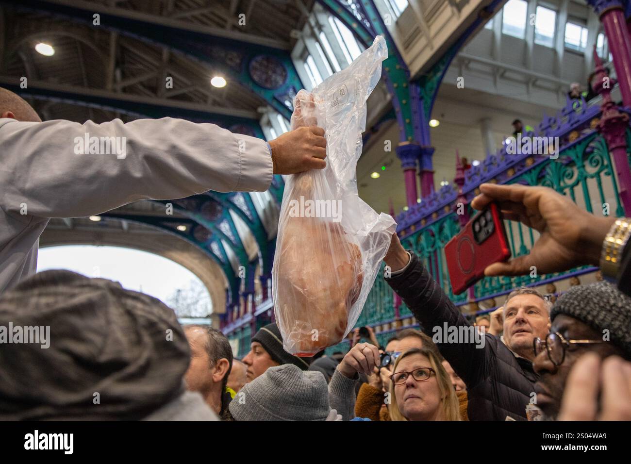 A butcher hands a joint of meat to a customer. In a tradition that is ...